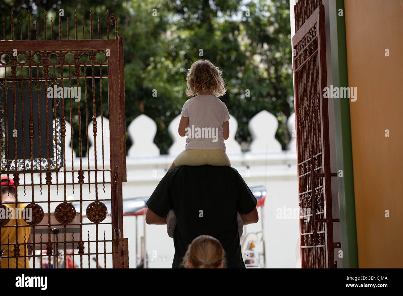 Tourist family exploring Thai temple, daughter riding on father's ...