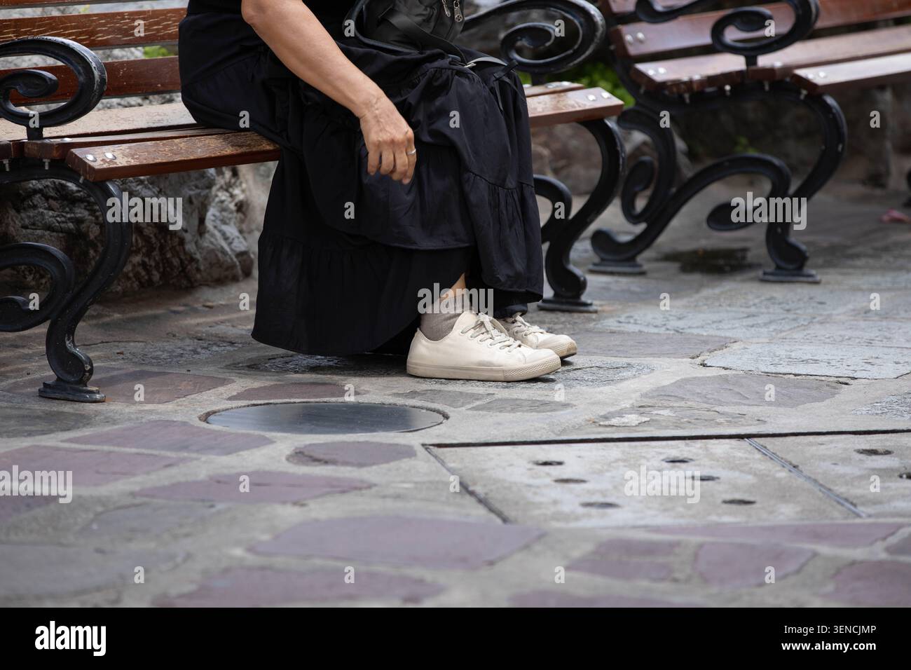 Woman in black dress and white sneakers sitting and resting, high angle ...
