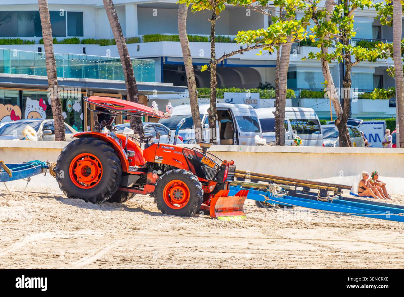Farm vehicle moving across sandy beach in tropical landscape with palm ...