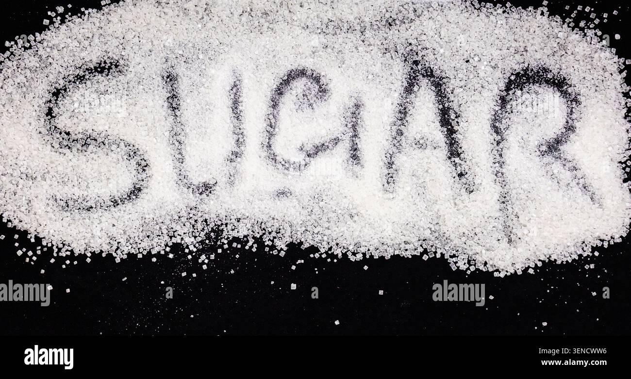 sugar word revealed through granulated sugar crystals on black ...