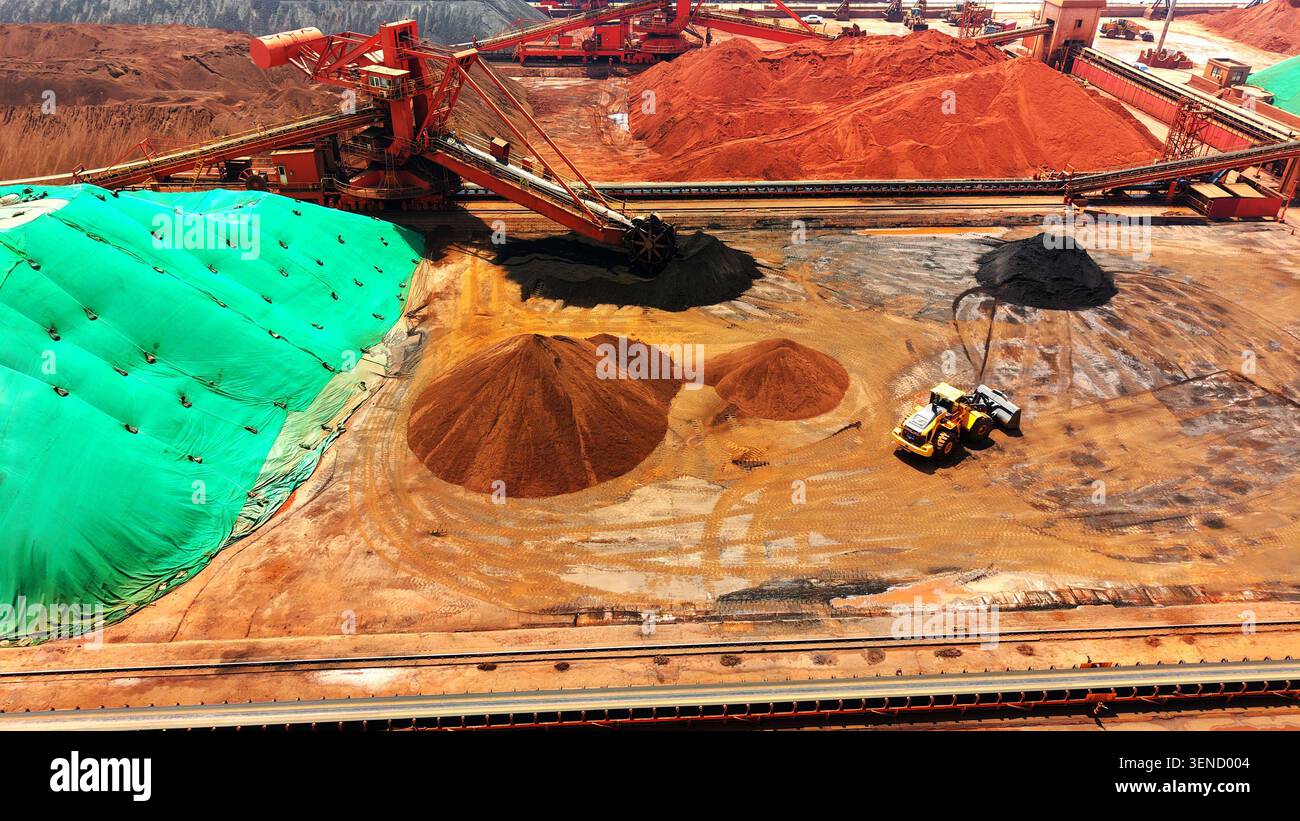 Workers spray water to suppress dust at the ore yard of Qingdao Port in ...