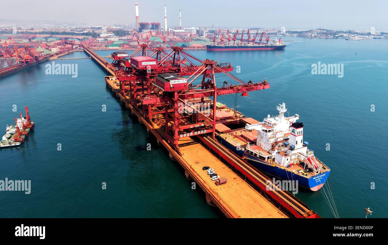 Workers spray water to suppress dust at the ore yard of Qingdao Port in ...