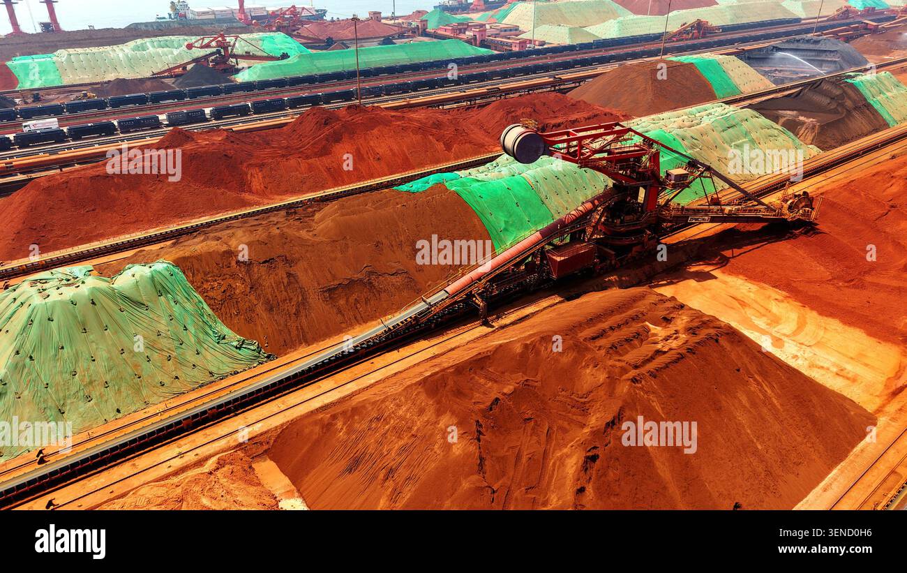 Workers spray water to suppress dust at the ore yard of Qingdao Port in ...