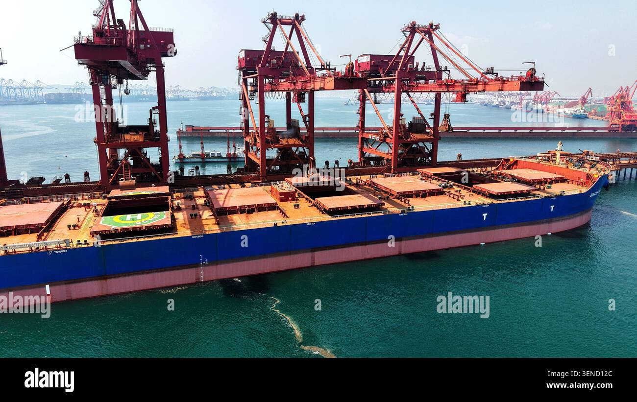 Workers spray water to suppress dust at the ore yard of Qingdao Port in ...