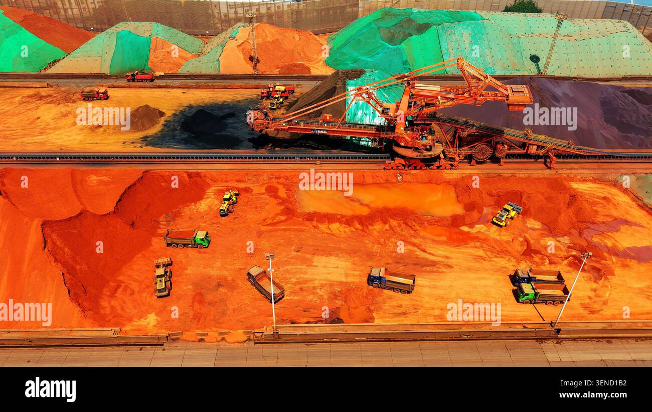 Workers spray water to suppress dust at the ore yard of Qingdao Port in ...