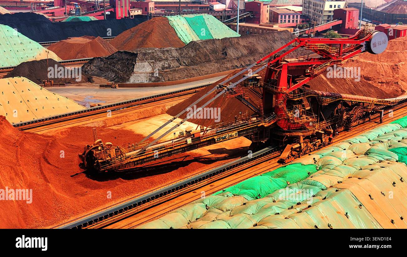 Workers spray water to suppress dust at the ore yard of Qingdao Port in ...