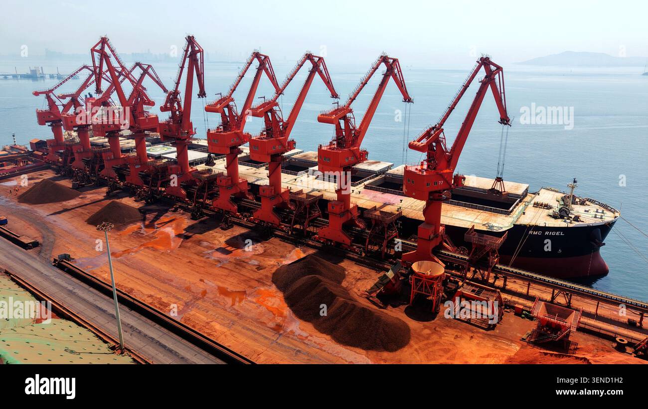 Workers spray water to suppress dust at the ore yard of Qingdao Port in ...