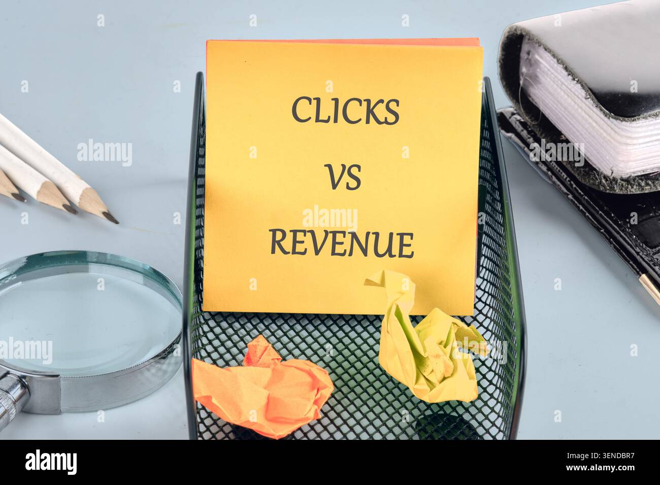A vibrant workspace displays a notepad with the words clicks vs revenue ...