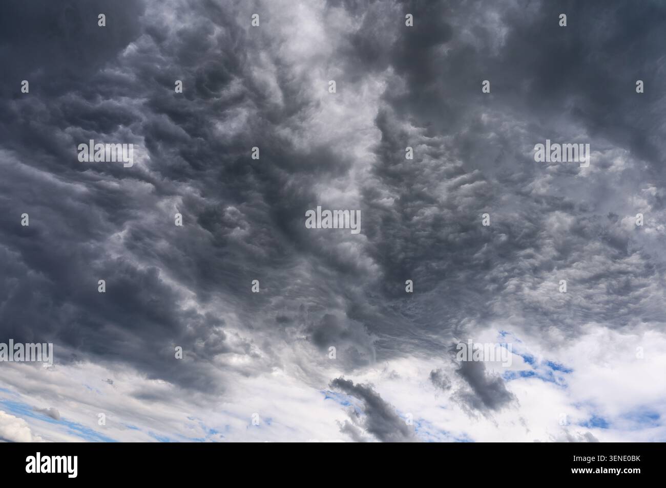 Heavy dark storm clouds covering the sky with patches of blue light ...