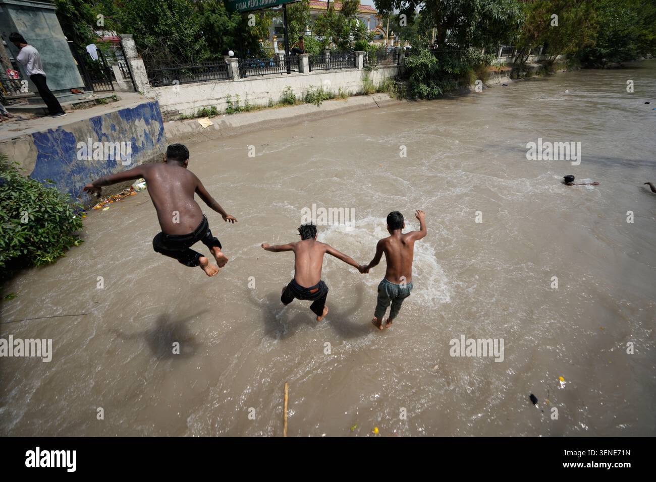 Children jump into a water canal to cool themselves on a hot summer day ...