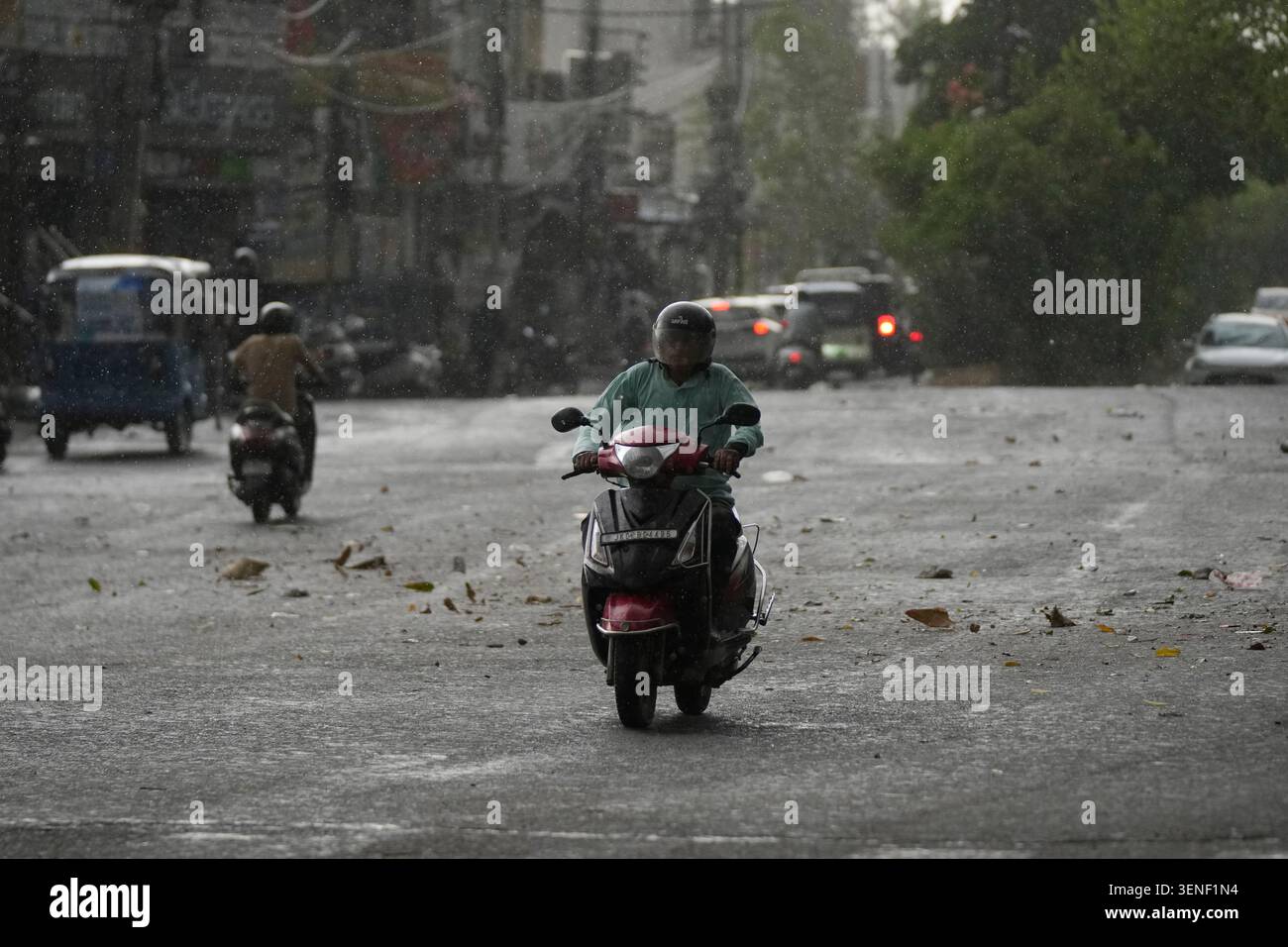 A scooterist rides through a dust storm accompanied by rain in Jammu ...