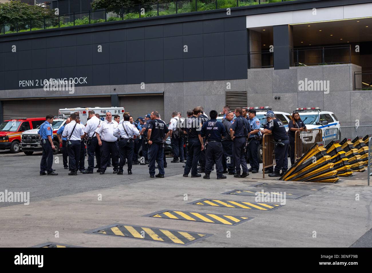 A group of FDNY and EMS personnel stand near emergency vehicles at Penn ...