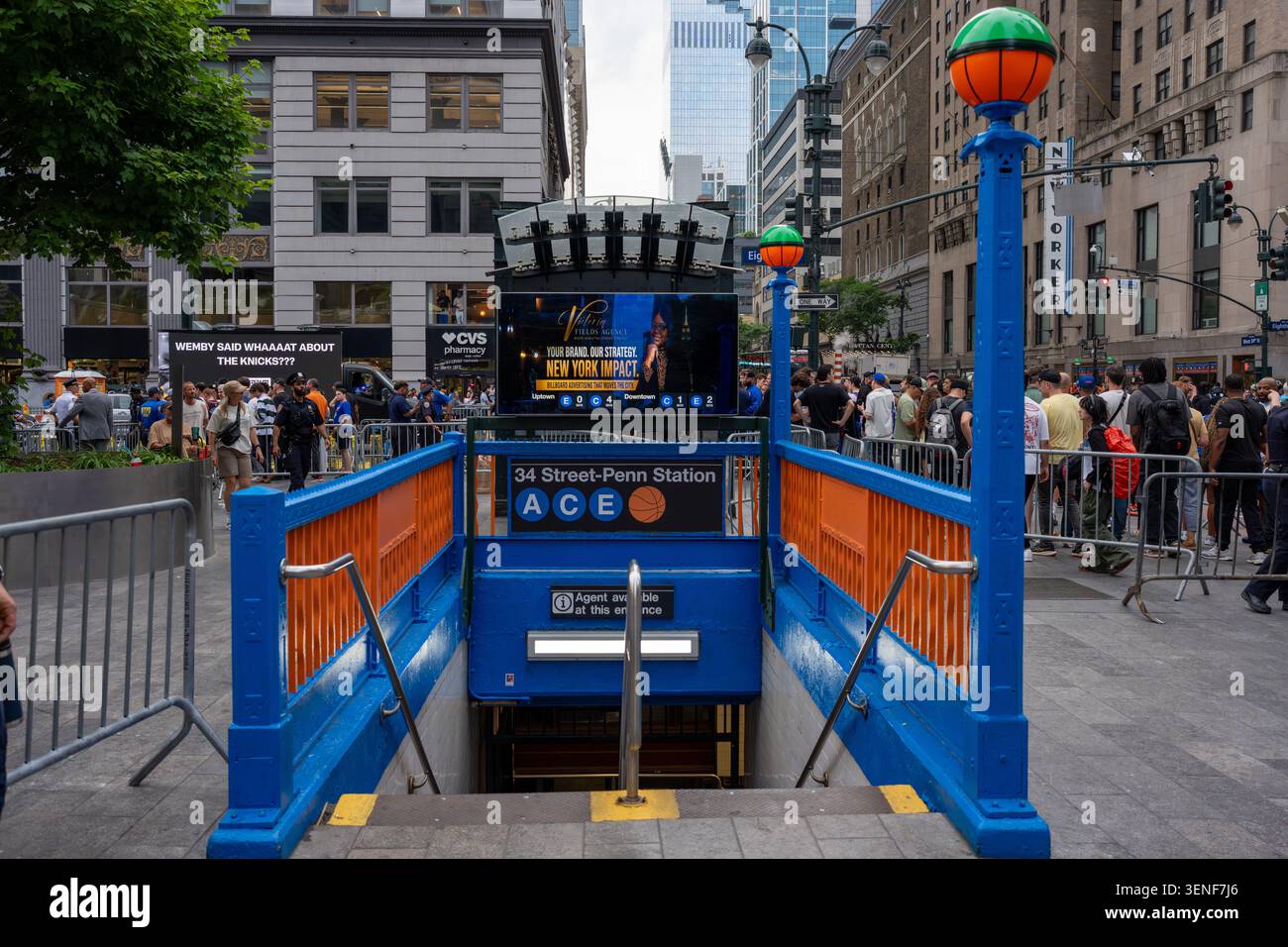 A bright blue and orange subway entrance with a large digital billboard ...