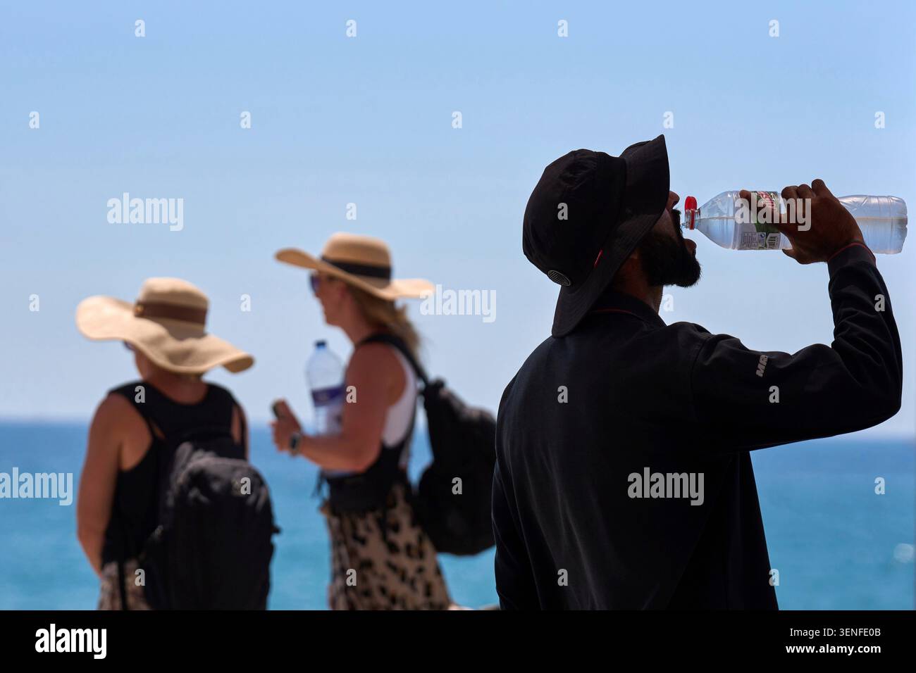 FILE - A tourist drinks water on a hot day at the beach in Barcelona ...