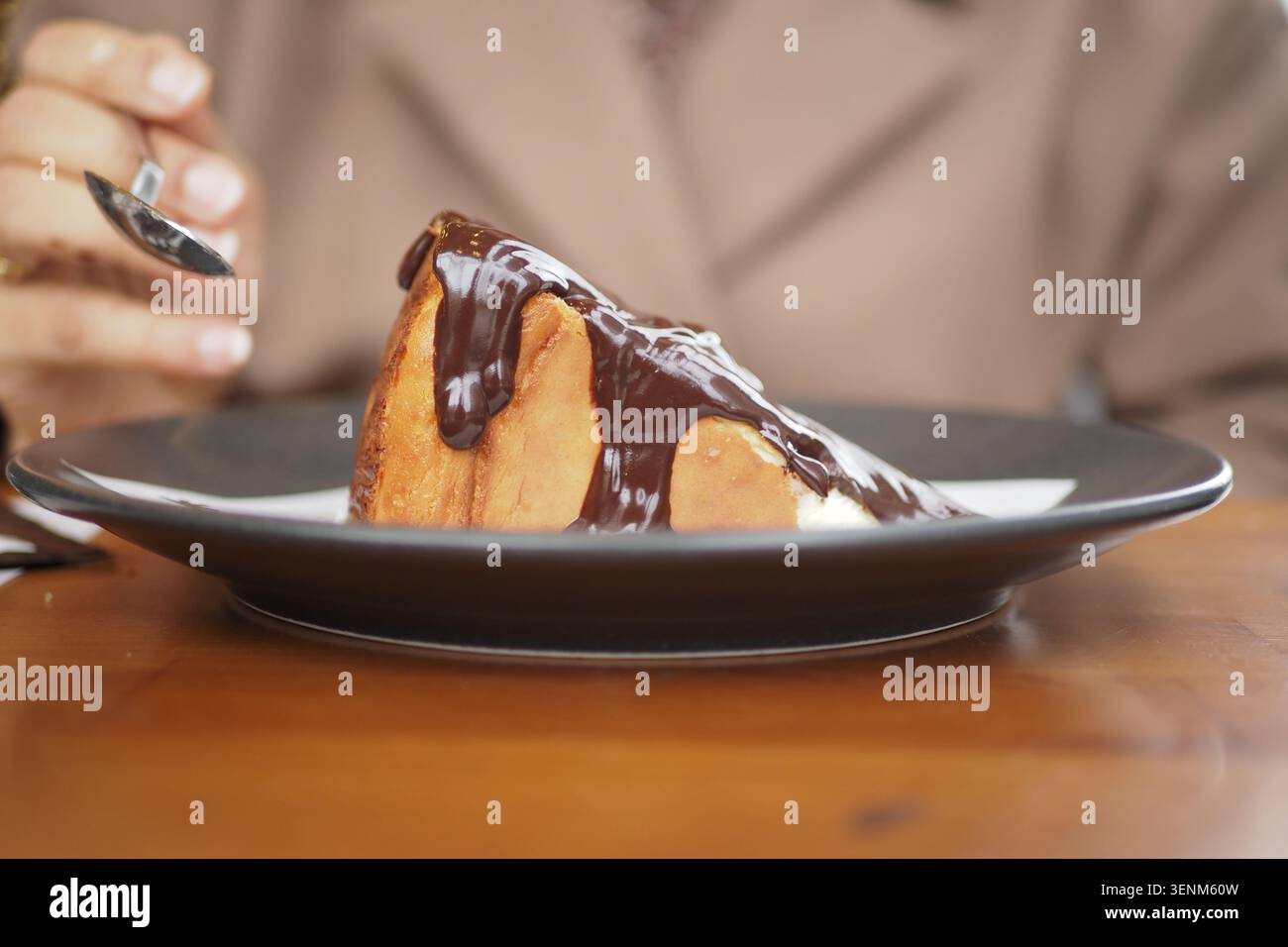 Enjoying a slice of chocolate cake on a wooden table Stock Photo - Alamy