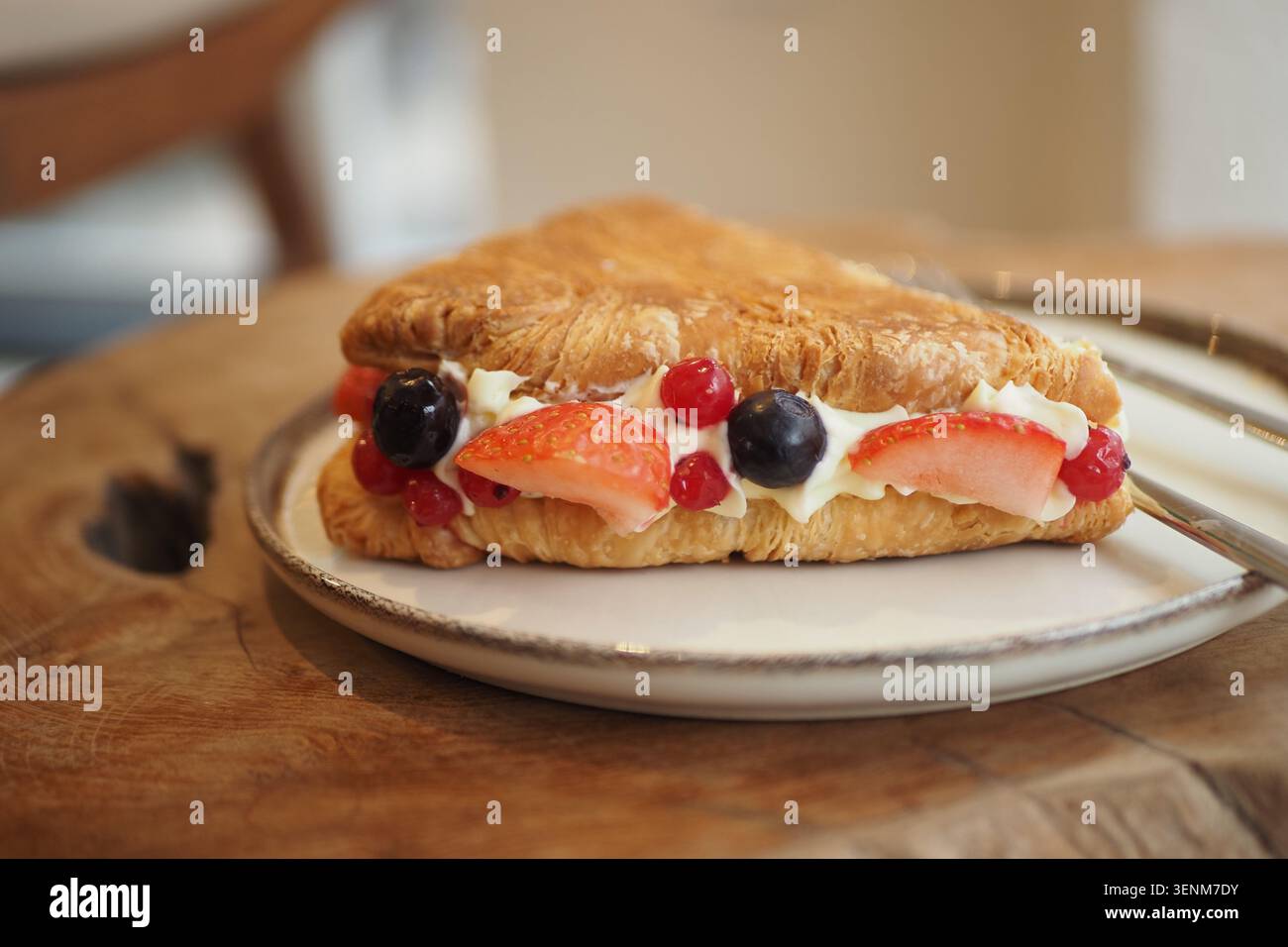 Croissant filled with cream and fresh berries on a plate Stock Photo ...