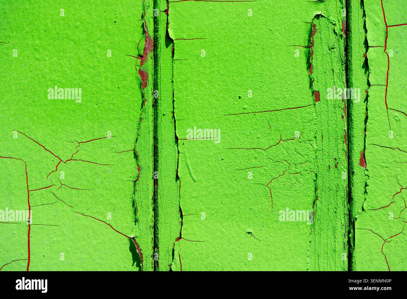 Peeling lime green paint exposing cracked red wood surface creating an ...