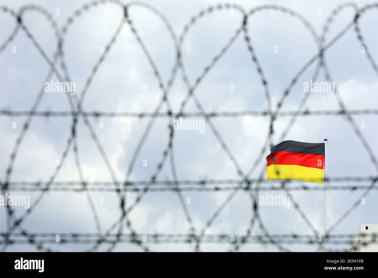 13.06.2026, Deutschland. Deutsche Flagge hinter einem Stacheldrahtzaun ...