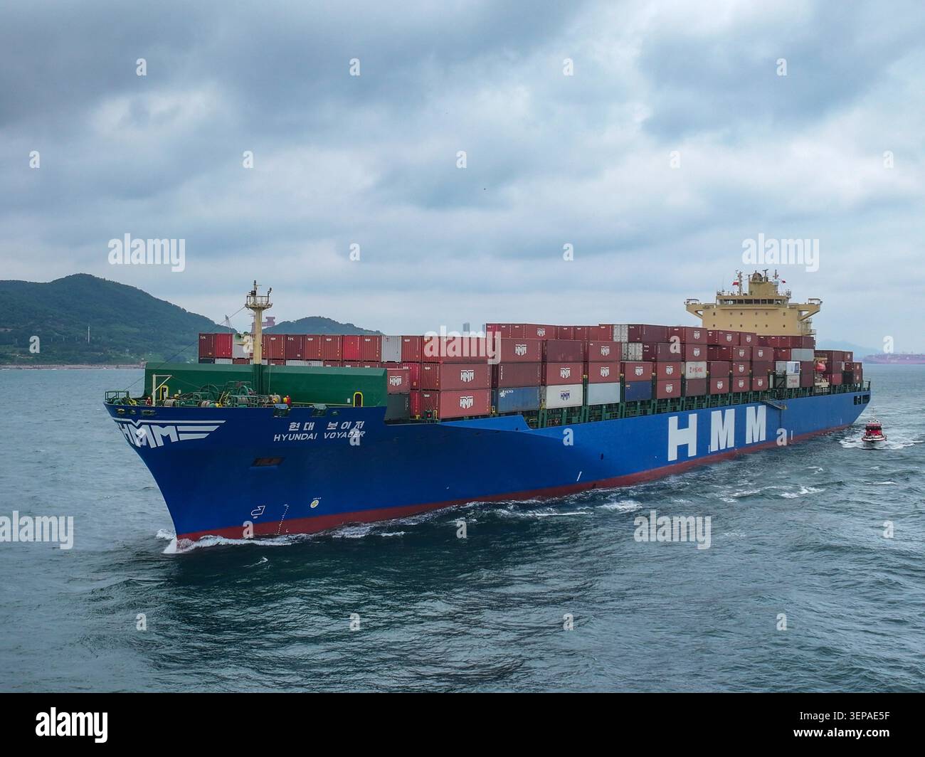A large ONE container ship and an HMM cargo ship navigate Qingdao Port ...