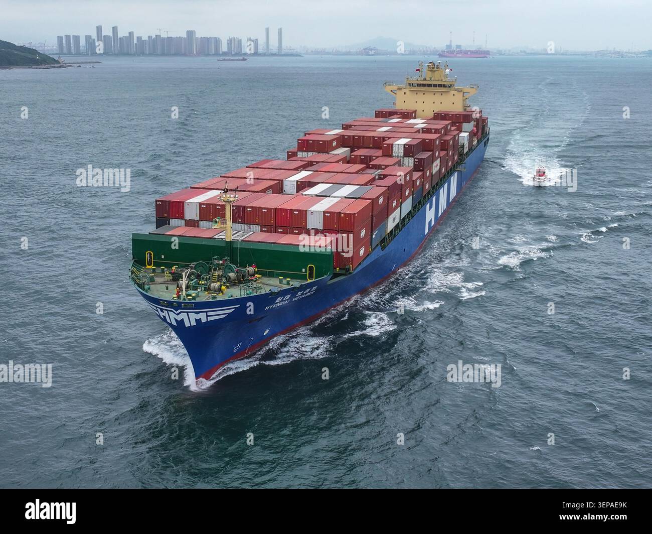 A large ONE container ship and an HMM cargo ship navigate Qingdao Port ...
