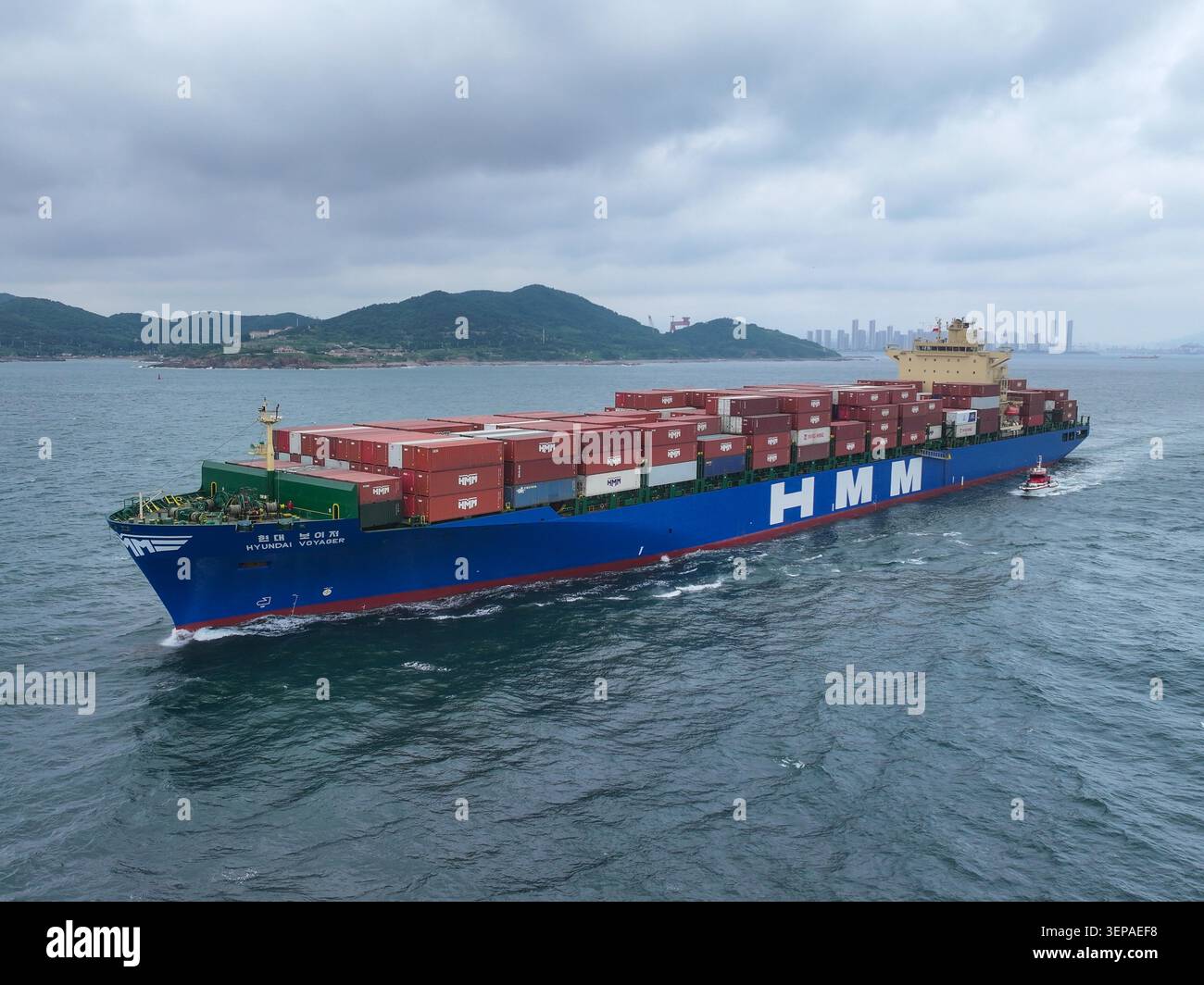 A large ONE container ship and an HMM cargo ship navigate Qingdao Port ...