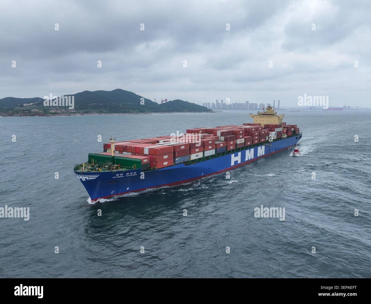 A large ONE container ship and an HMM cargo ship navigate Qingdao Port ...
