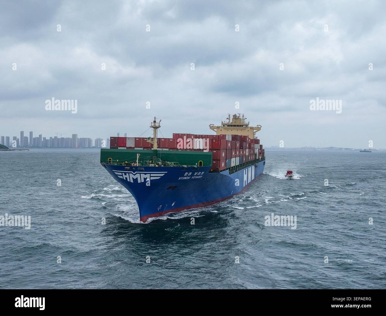 A large ONE container ship and an HMM cargo ship navigate Qingdao Port ...