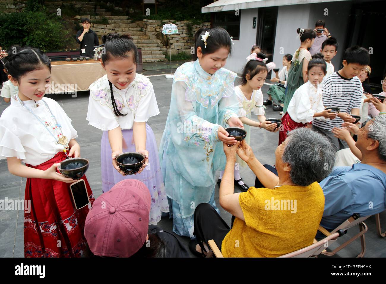 Children serve tea to elders during a Dragon Boat Festival themed event ...