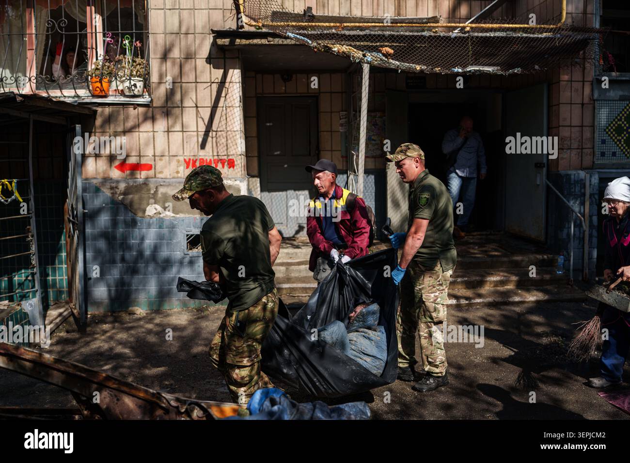 Policemen carry the dead body of a woman killed inside a residential ...
