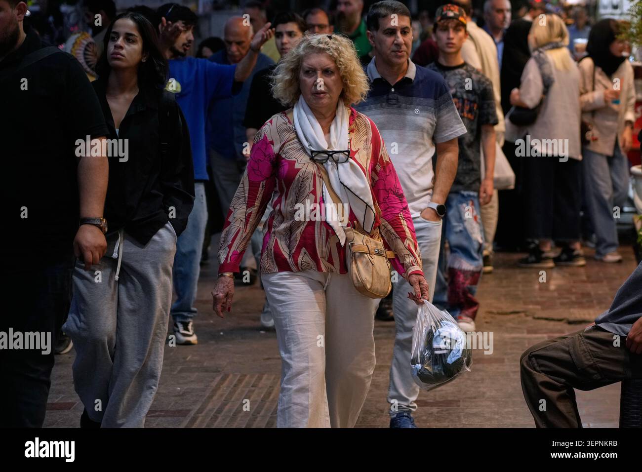 People walk on a sidewalk at Tajrish square in northern Tehran, Iran ...