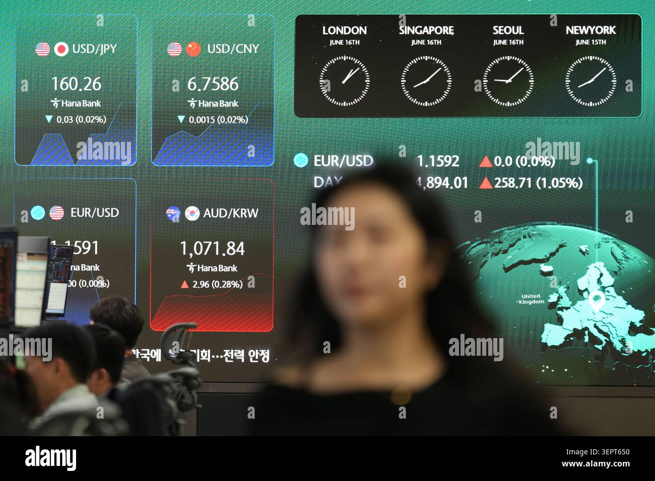 A dealer walks past near the screens showing the foreign exchange rates ...