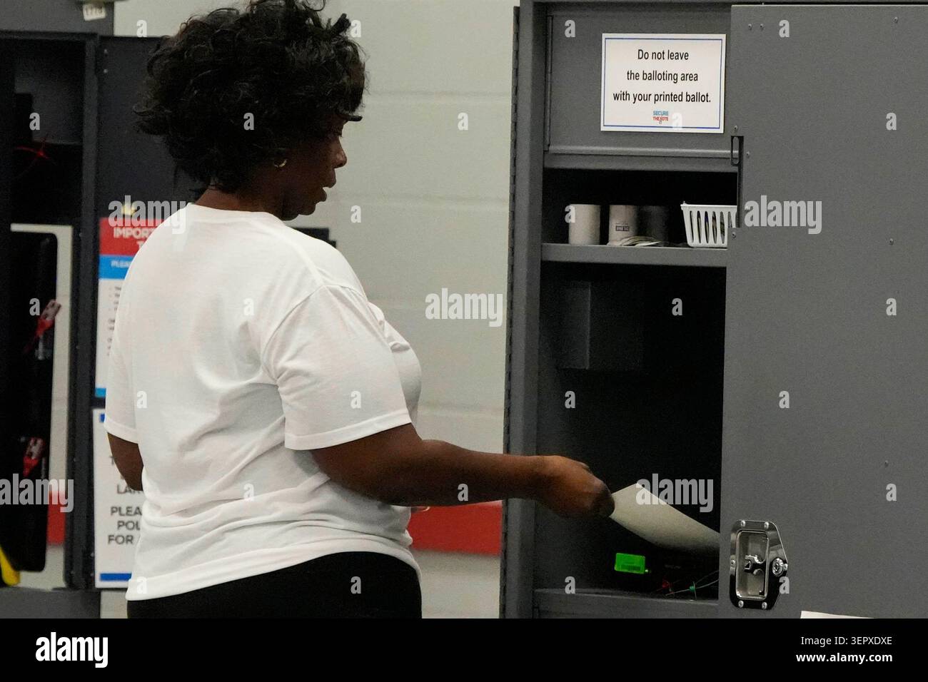 A woman places her paper ballot into a machine after voting in a runoff ...