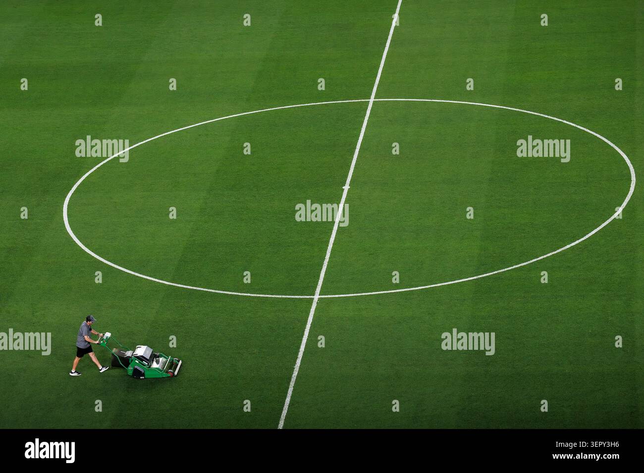 A groundsman cuts the grass of the pitch next to the center circle of ...