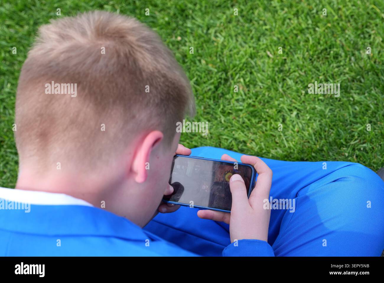 A young boy plays on his mobile phone in Ascot, England, Tuesday, June ...