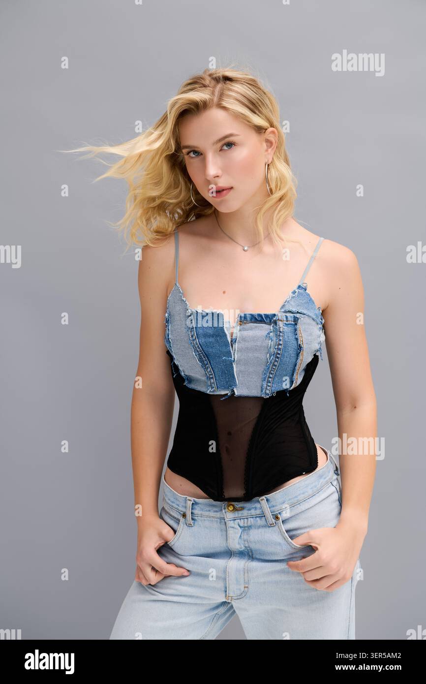 Captured in a sleek studio, a blonde woman showcases her trendy denim ...