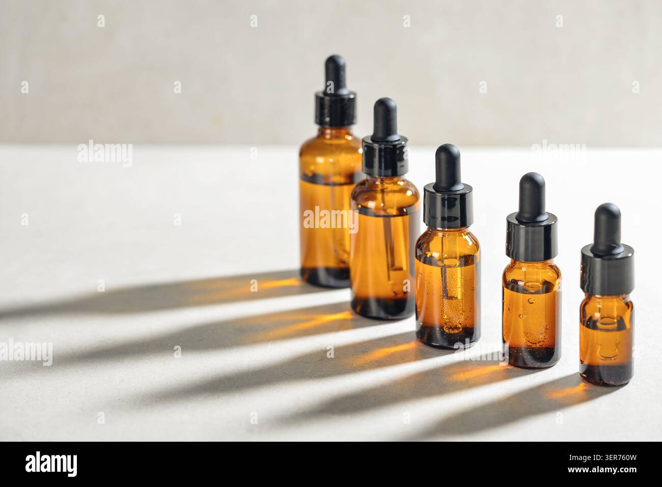 Amber glass dropper bottles of different sizes arranged in ascending ...