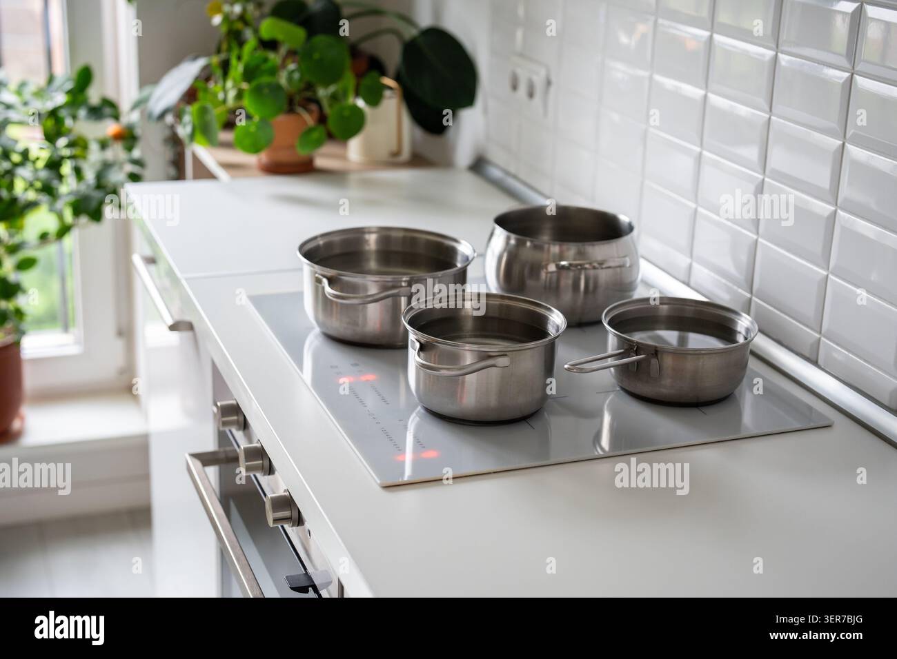 Pots filled with water heating on electric stove in kitchen, planned ...