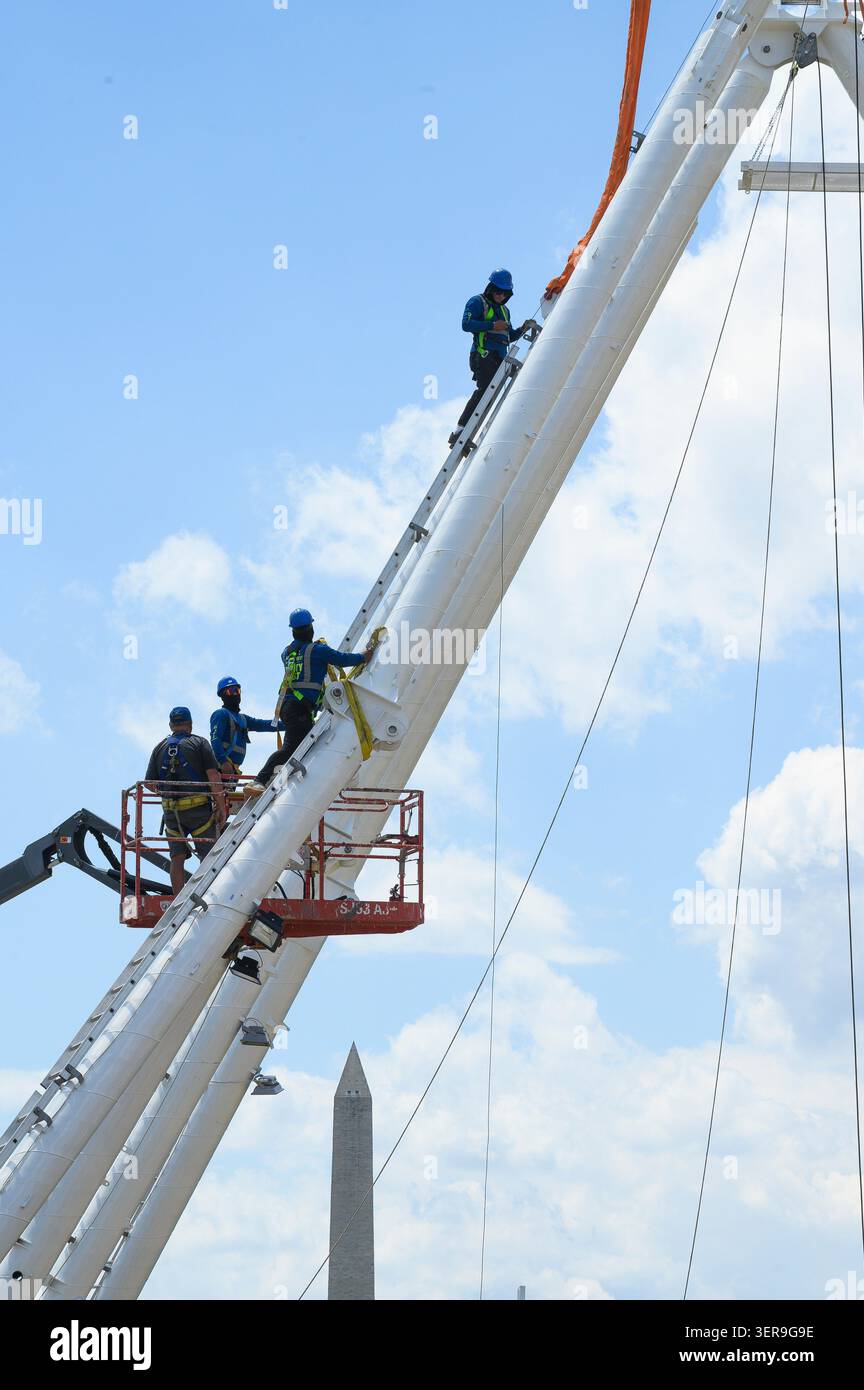 Workers secure a support leg of a 110-foot ferris wheel which is being ...