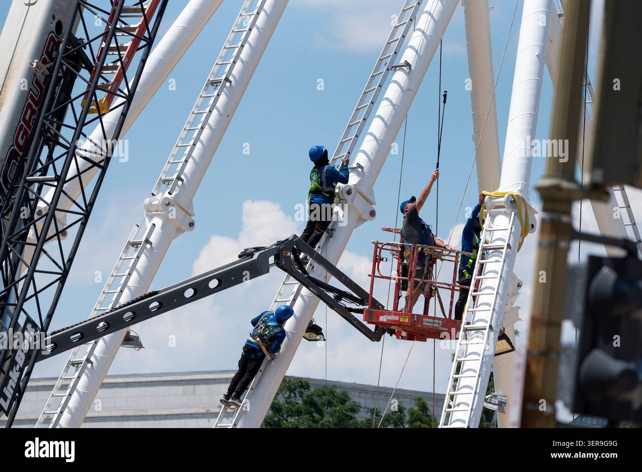 Workers secure a support leg of a 110-foot ferris wheel which is being ...