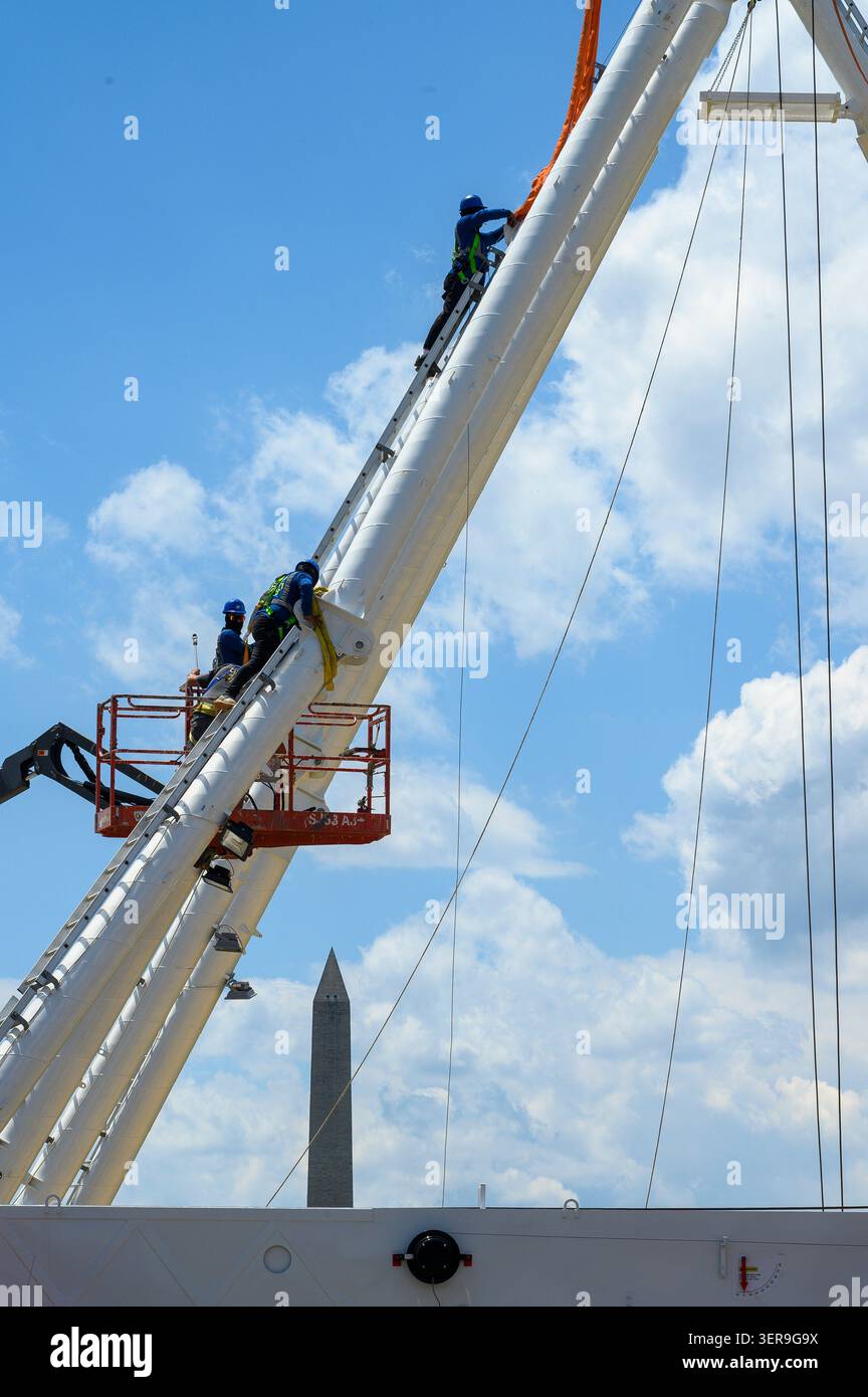 Workers secure a support leg of a 110-foot ferris wheel which is being ...