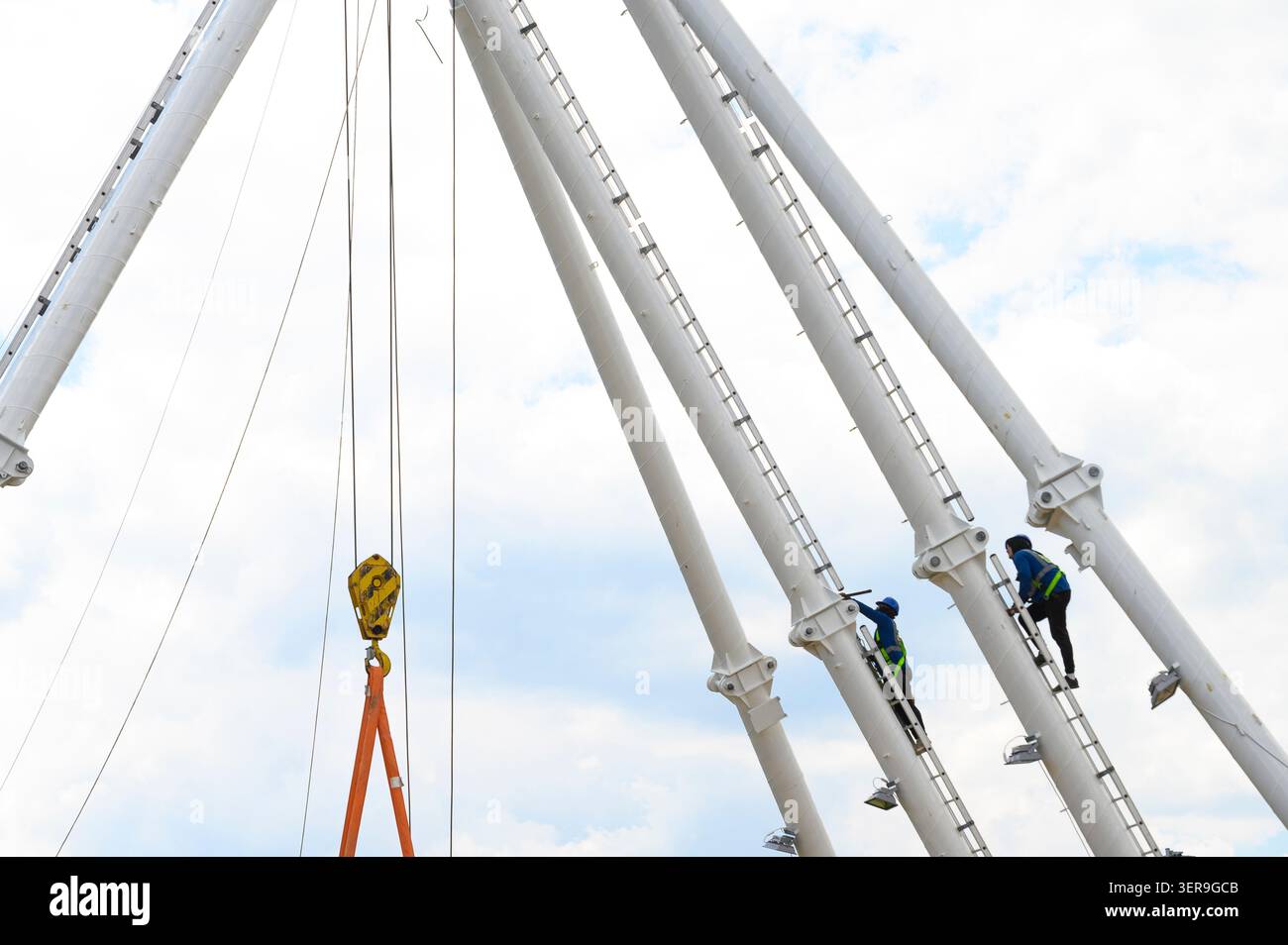 Workers secure a support leg of a 110-foot ferris wheel which is being ...