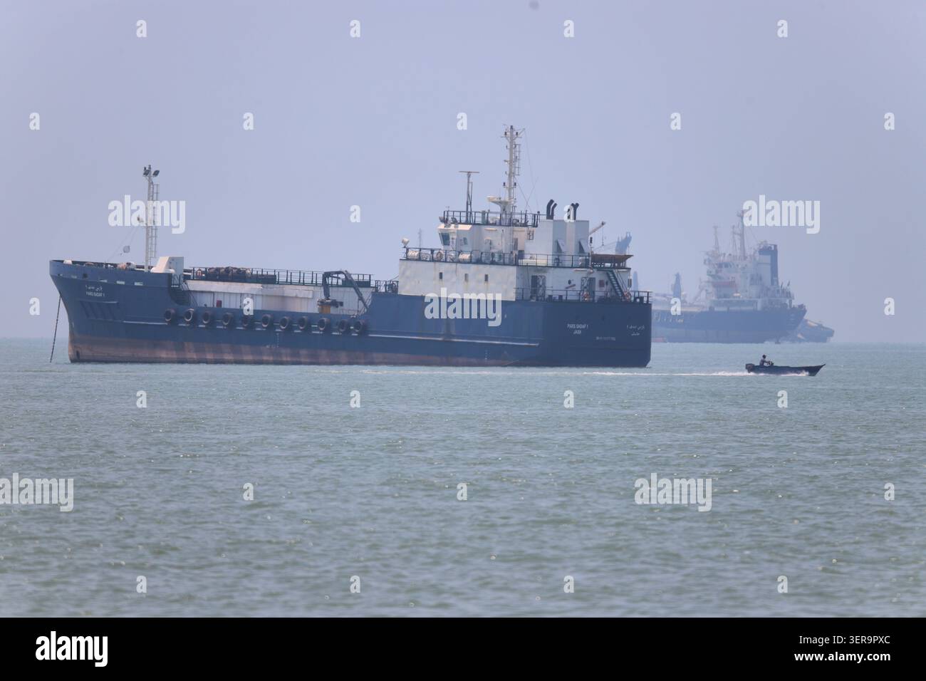 A small motorboat passes anchored vessels in the Strait of Hormuz off ...