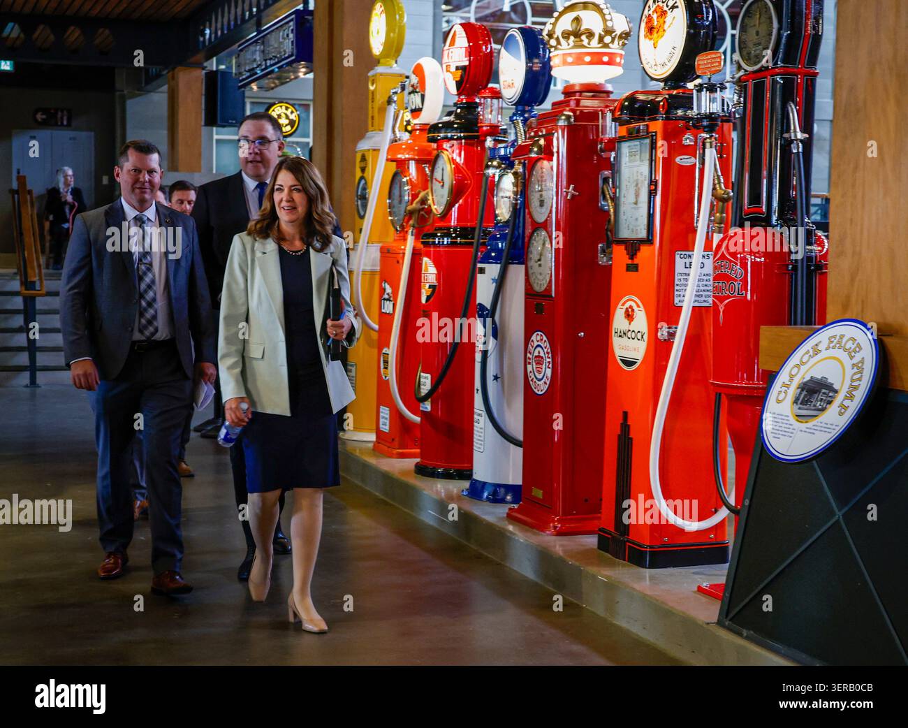 Alberta Premier Danielle Smith, right, walks past antique gas pumps to ...