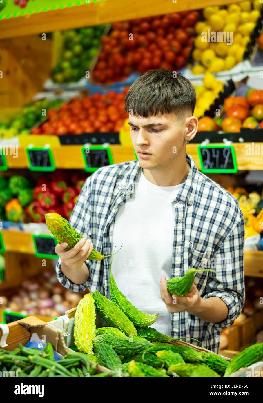 Portrait of man choosing fresh bitter melon (Momordica charantia) in ...