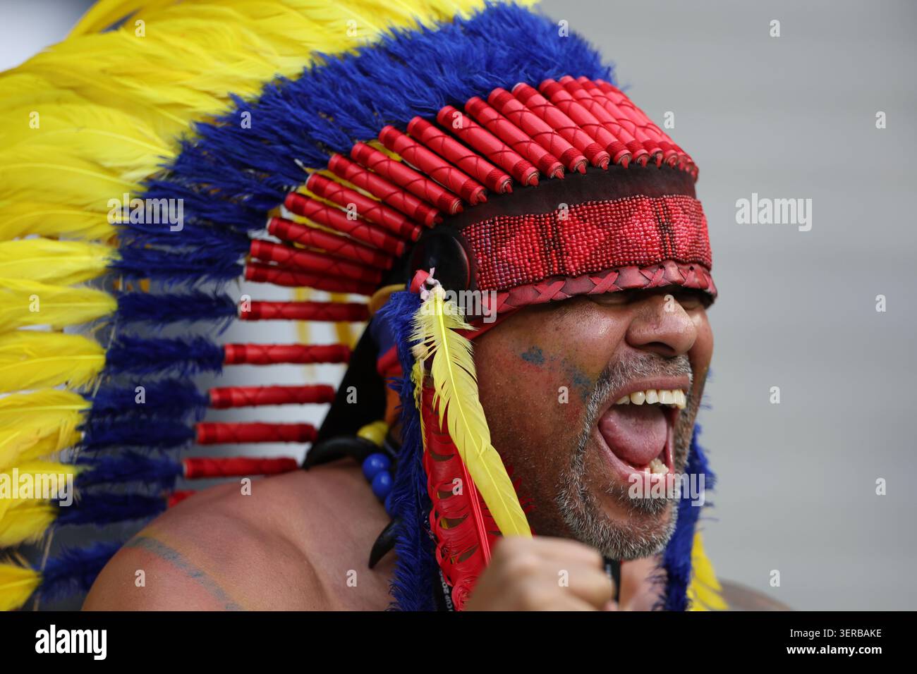 A Colombia fan wearing a colorful headdress yells prior to the start of ...