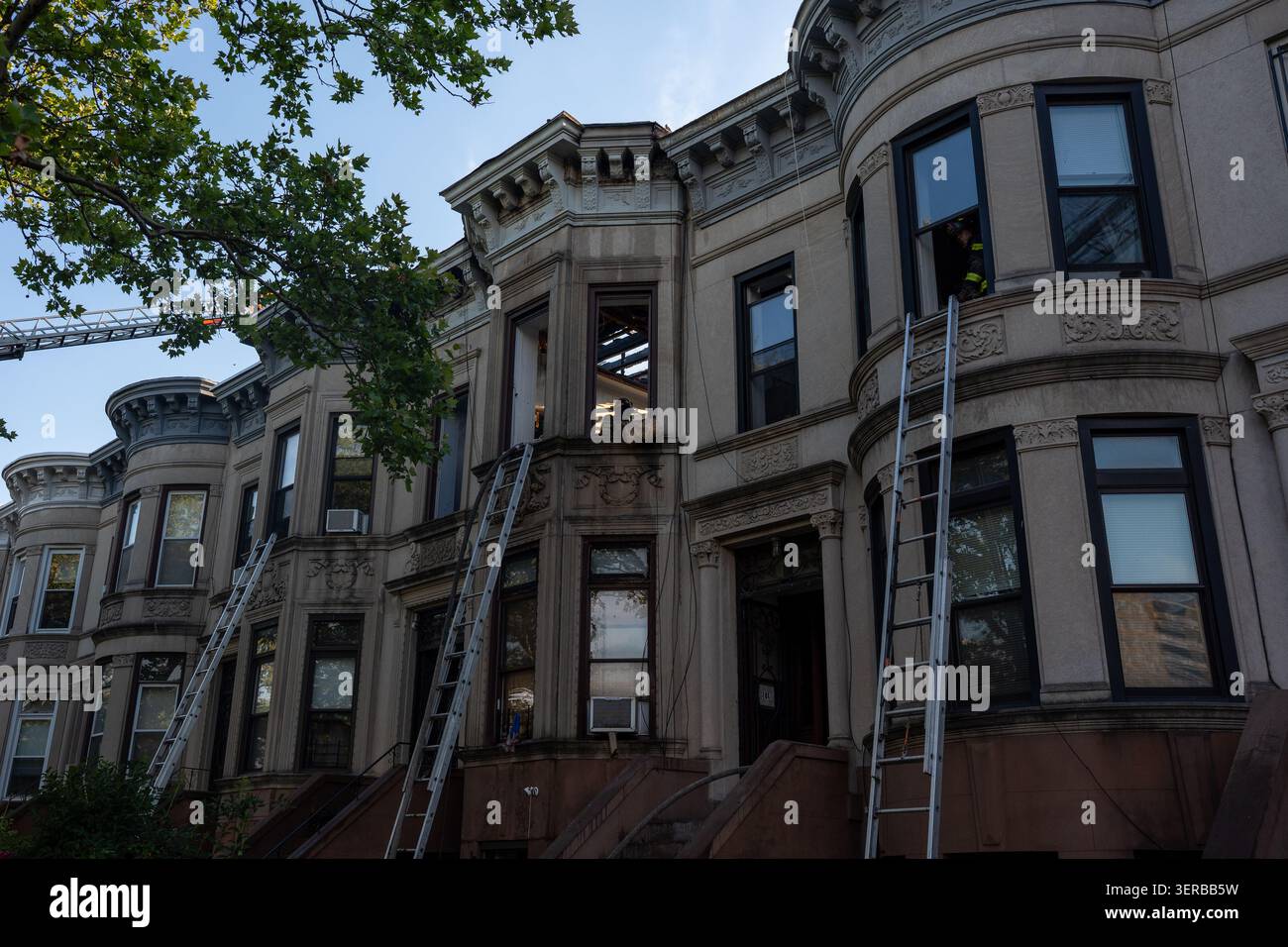 Firefighters are seen on ladders outside a damaged building, with some ...