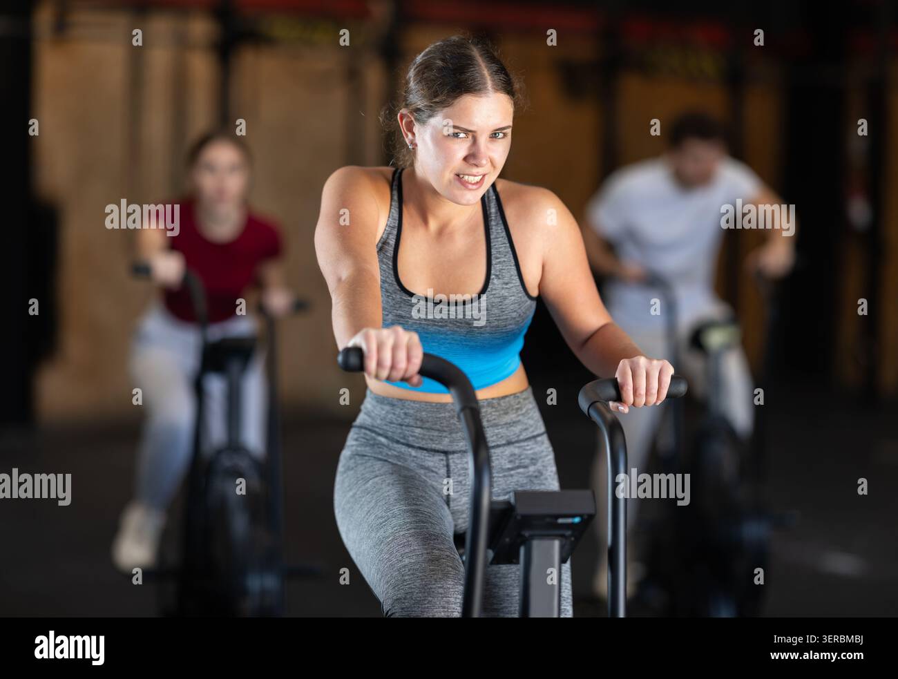 Focused girl works out with airbike during class at fitness club Stock ...