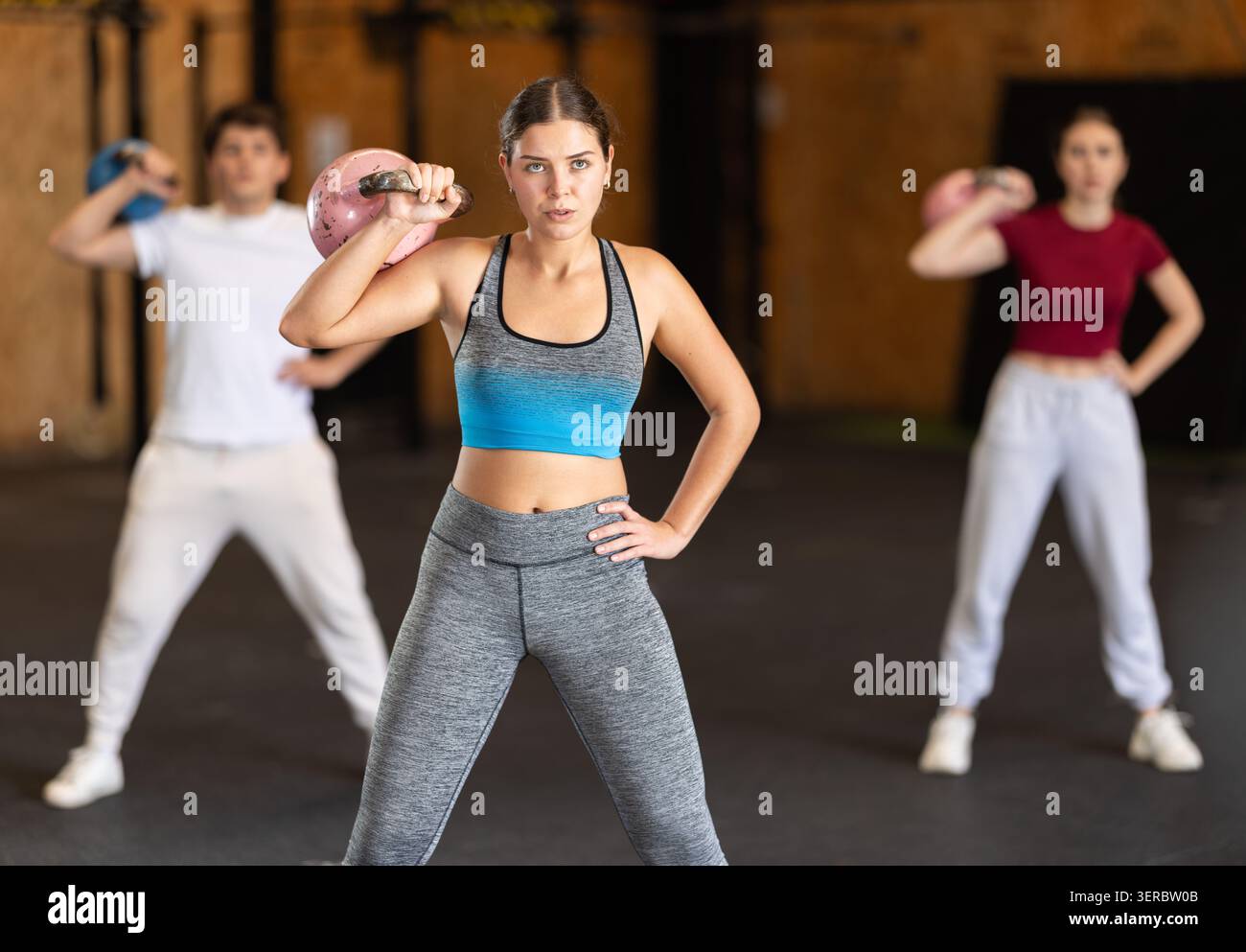 Girl in gym does exercises with kettlebell, lifts and lowers heavy ...