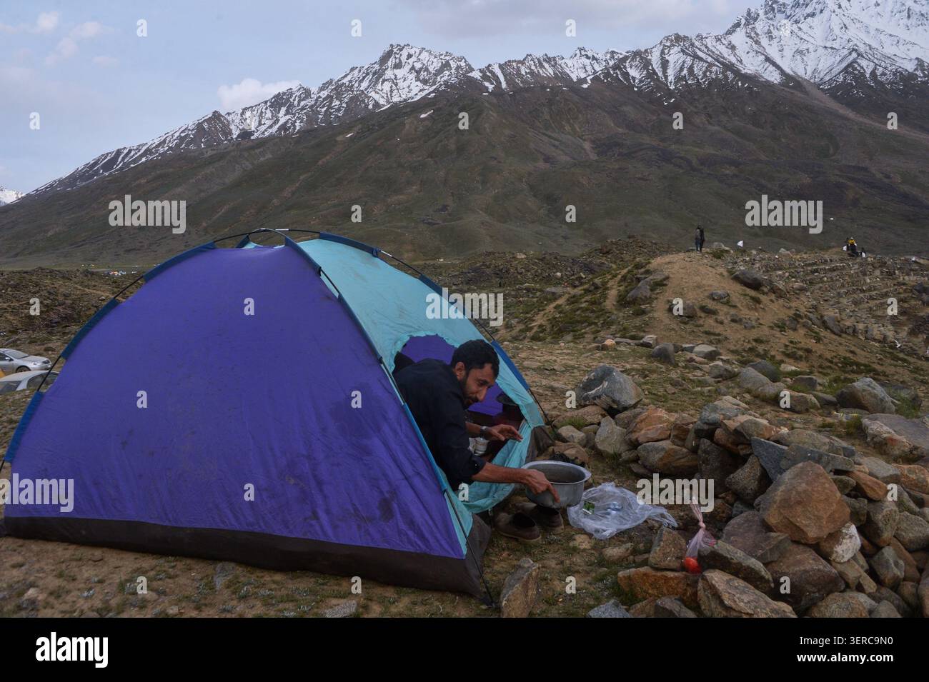 A spectator washes a dish after preparing tea in his tent during the ...