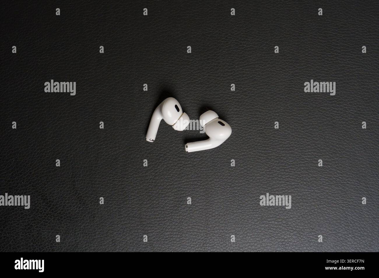 White earbuds rest on dark textured surface. Simple, clean design ...